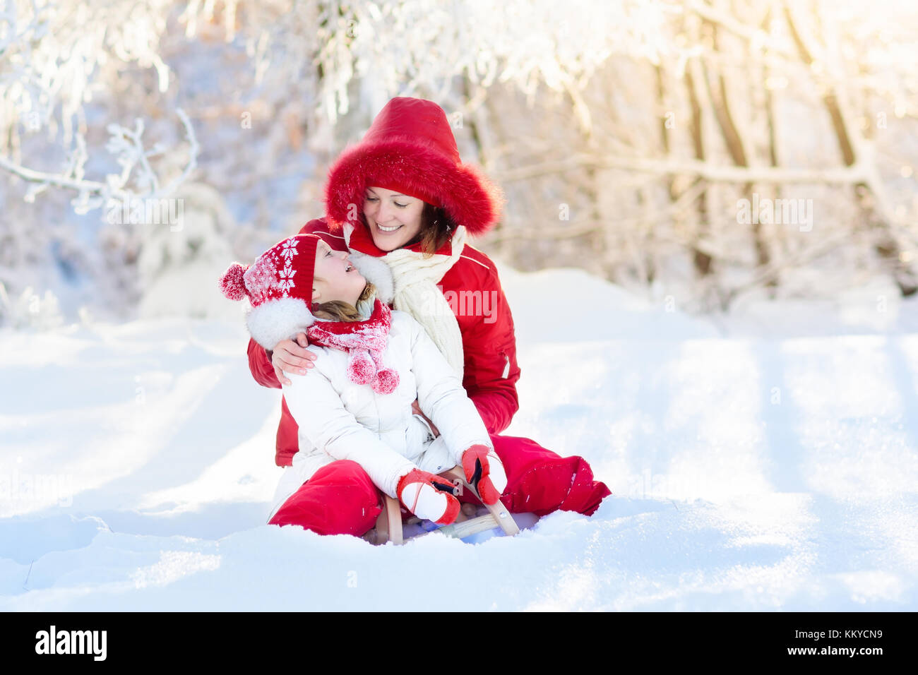 Mother and baby on sleigh ride. Child and mom sledding. Toddler kid ...