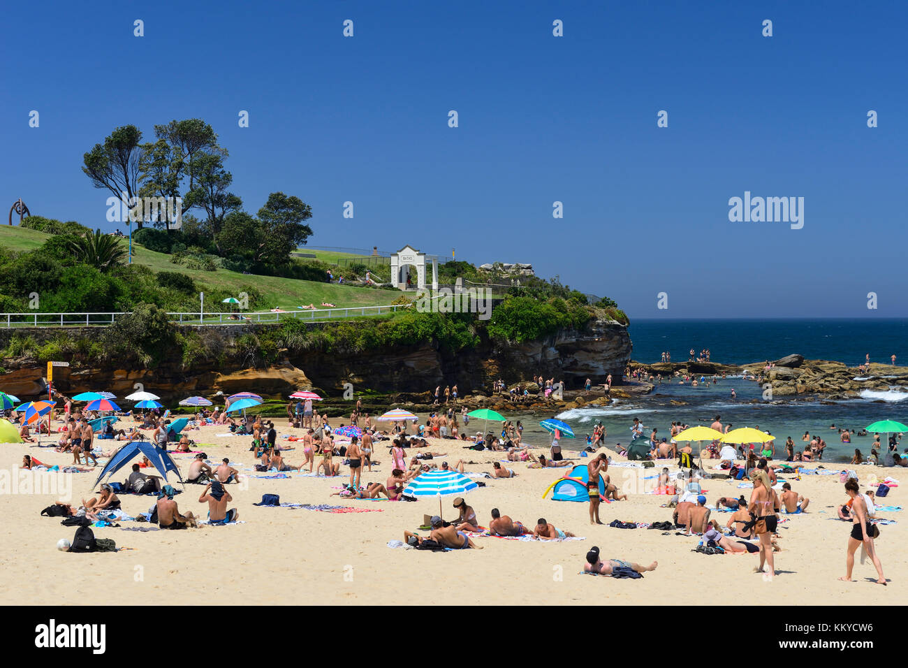 Sunbathers on Coogee Beach, with Dunningham Park on headland in ...