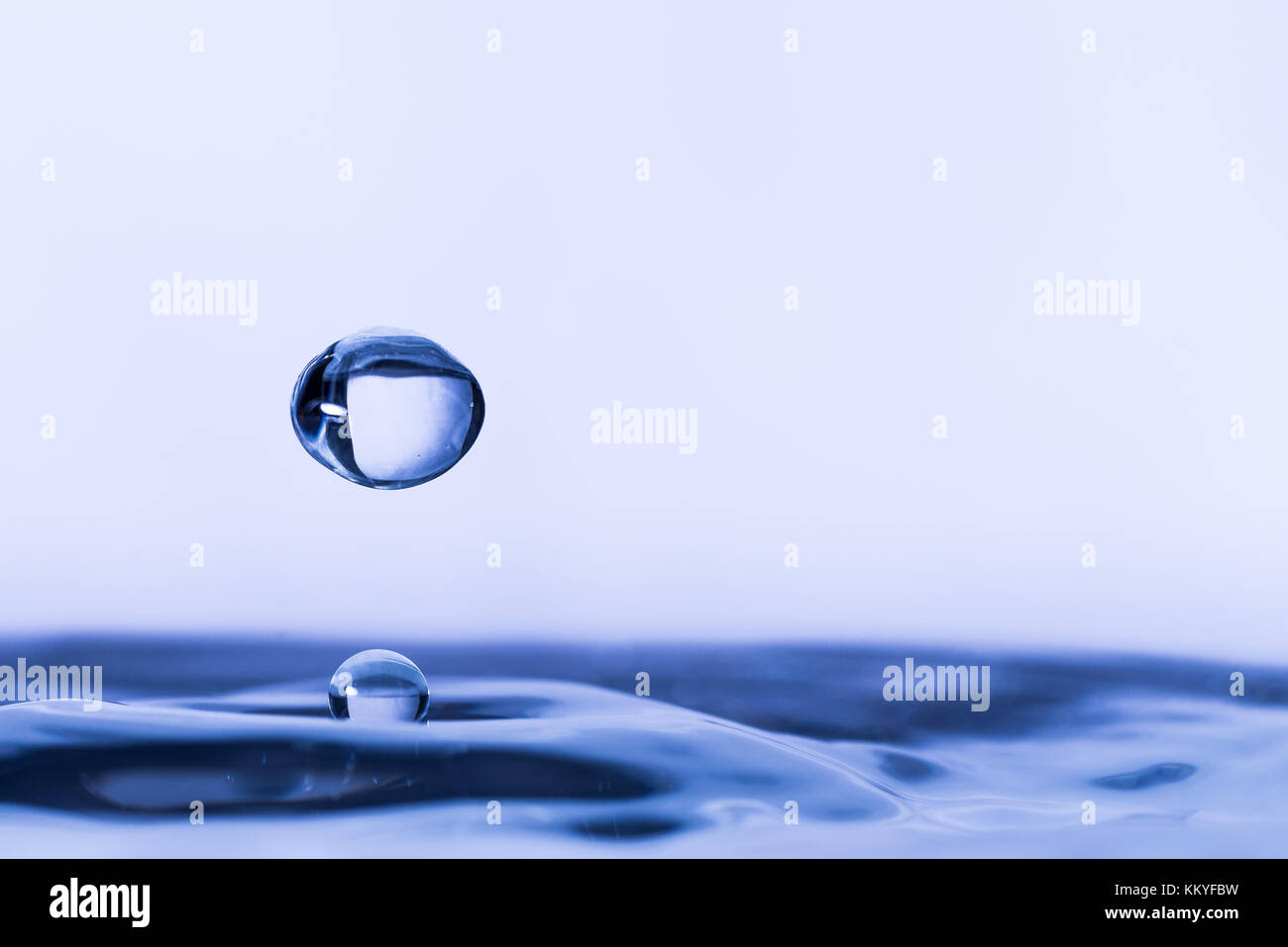 Close up of water drop dropping into water Stock Photo - Alamy