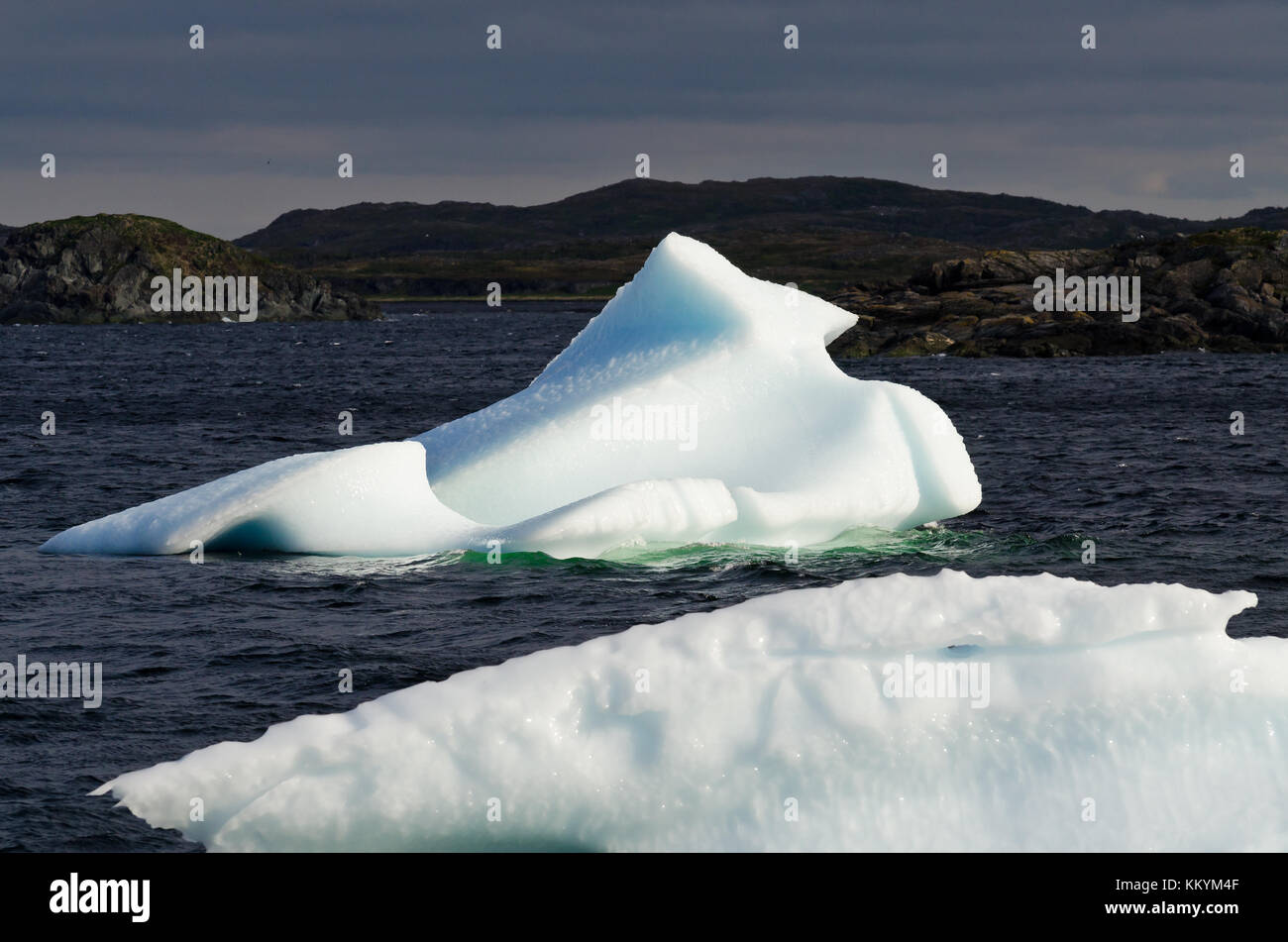 Bright white iceberg on dark water and rock background Stock Photo - Alamy