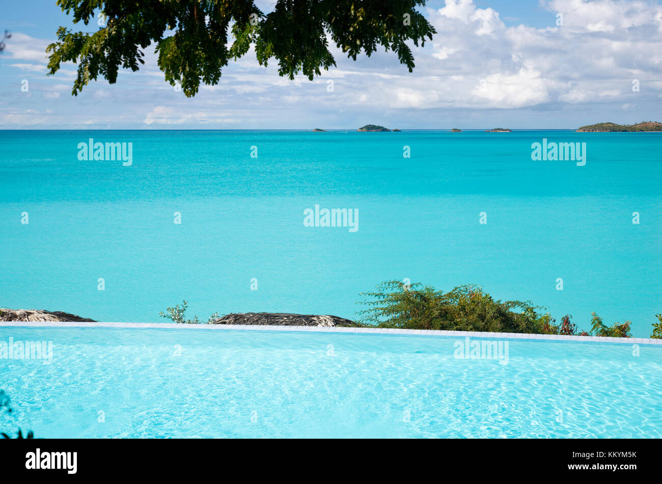 A hotel pool in Antigua above the turquoise water of the Caribbean Sea ...