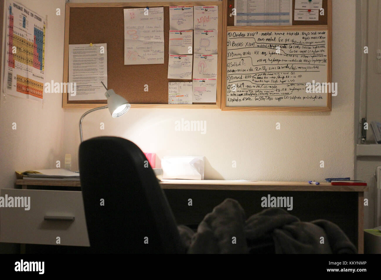 empty desk with periodic table and notice board on the wall with pins ...