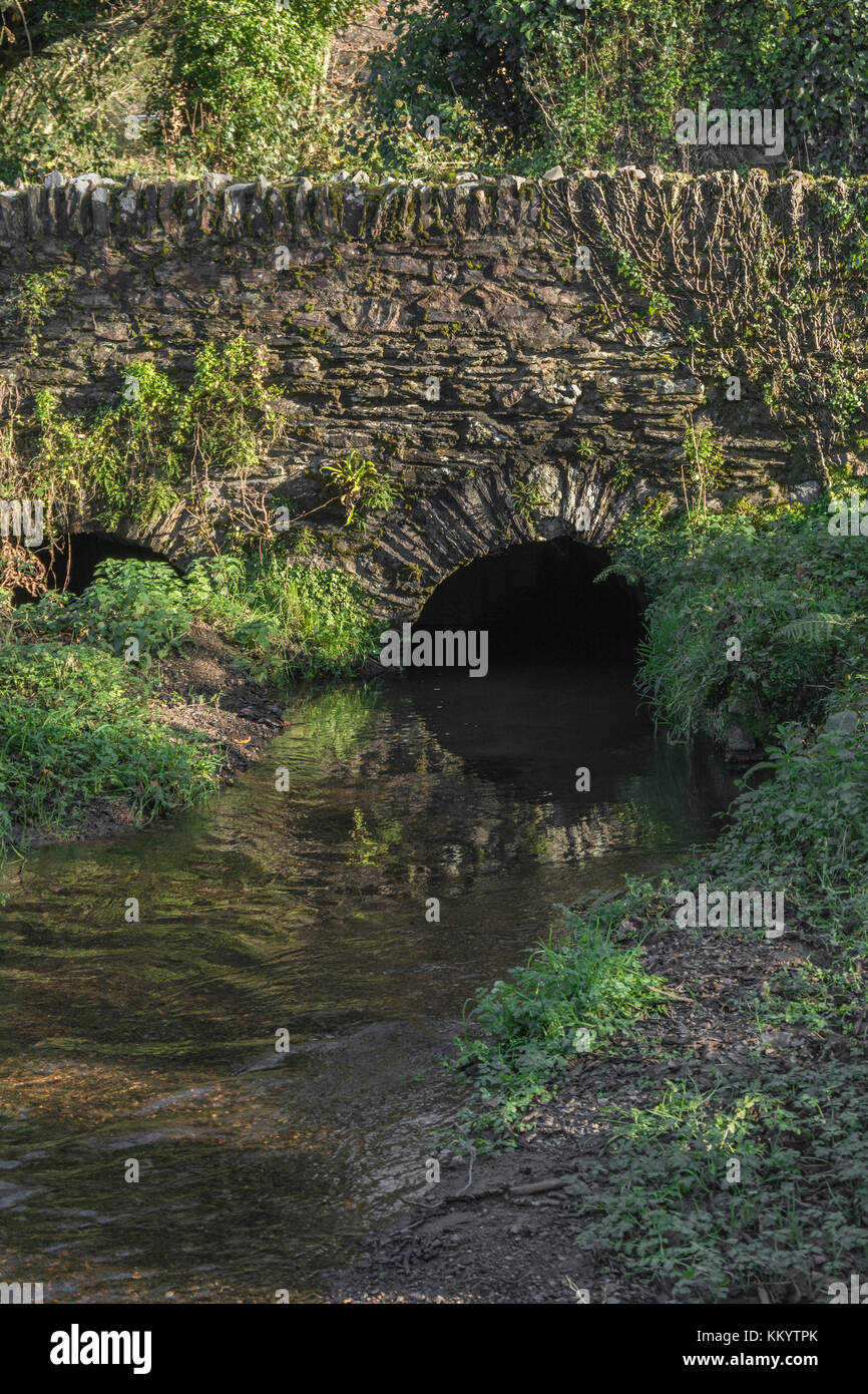 Small rural stone bridge arching over a small, clear-running, stream ...