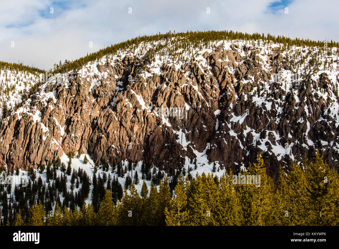 The sun rises over Tuff Cliff in winter at the Yellowstone National ...