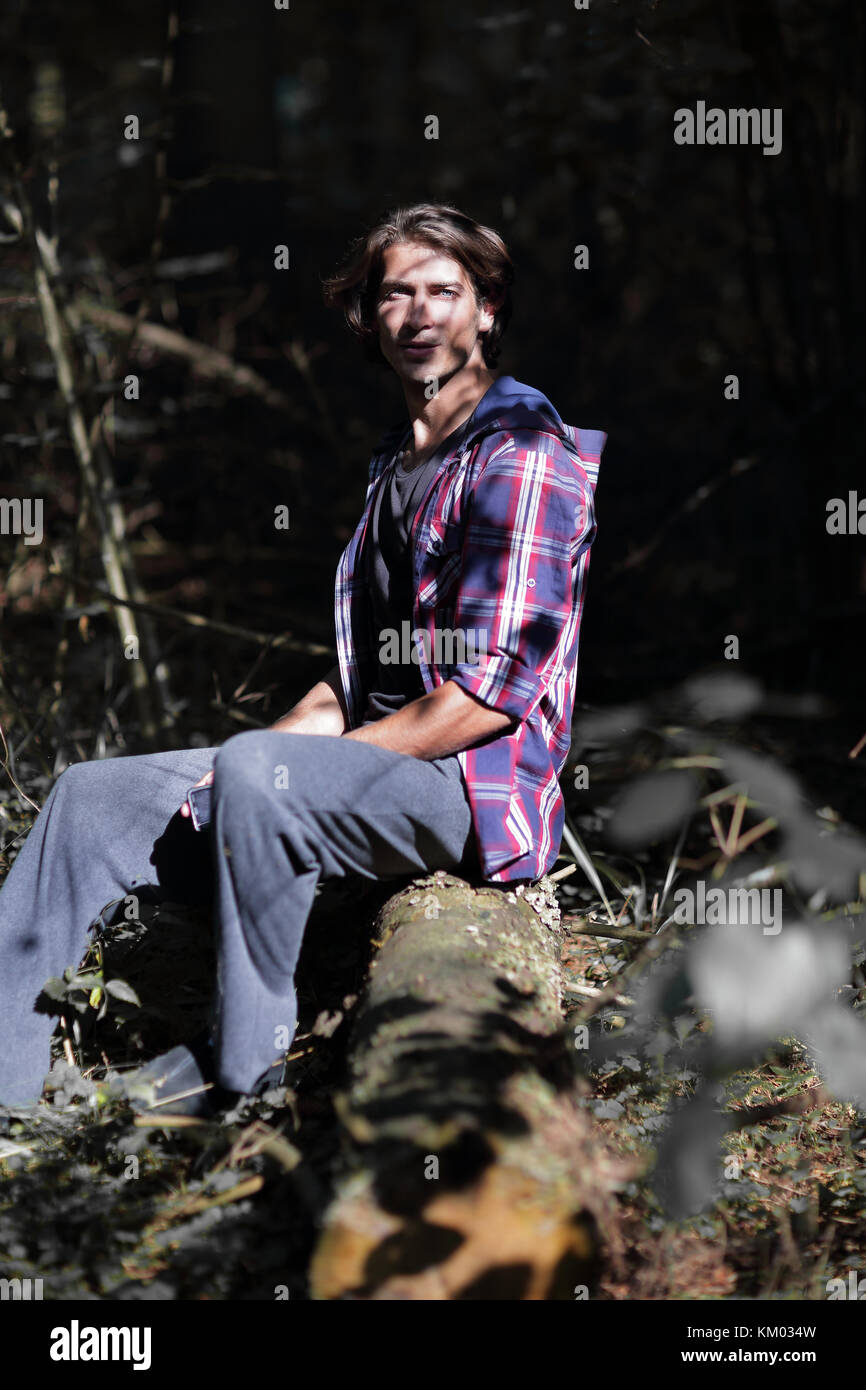 guy sitting on a log in the woods Stock Photo - Alamy