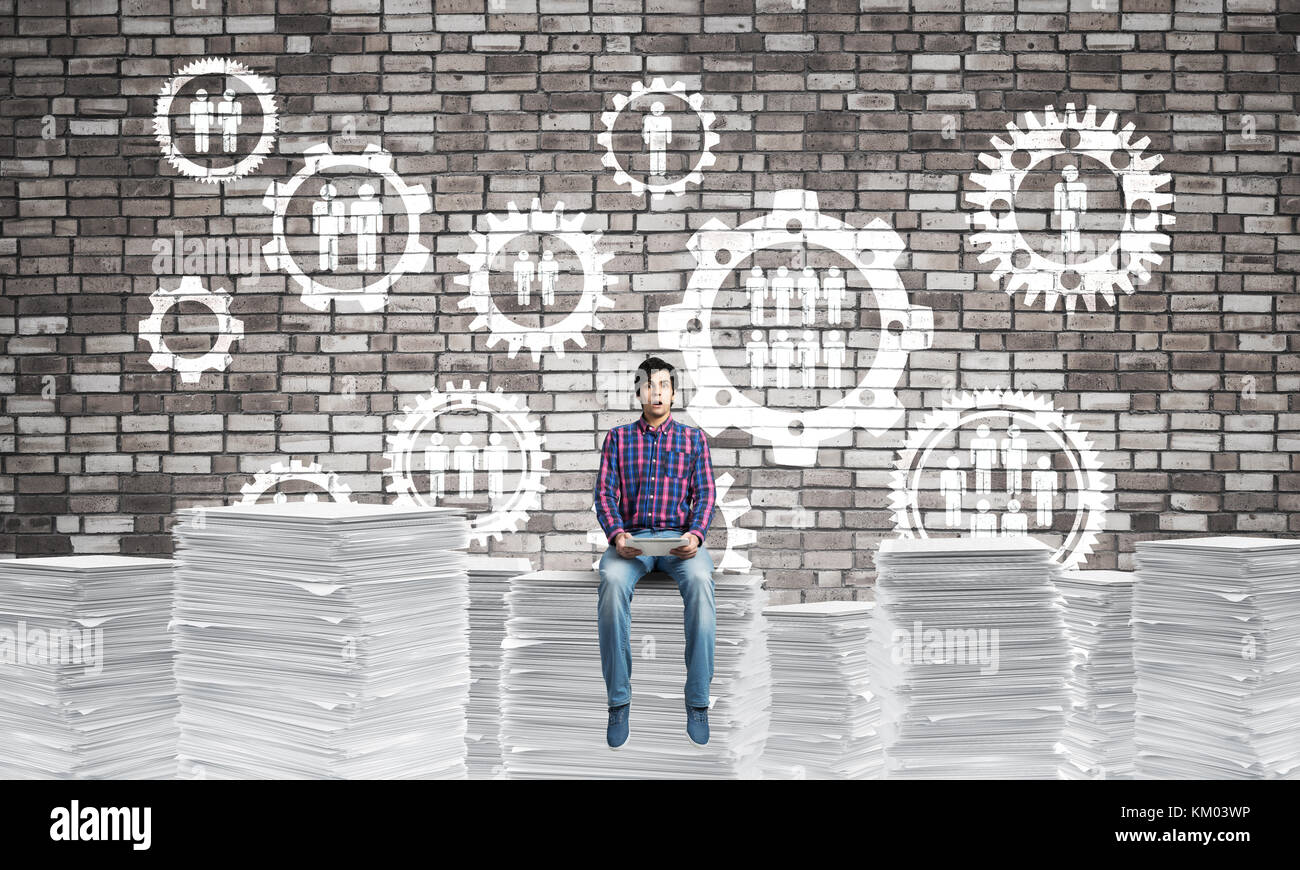 Attractive man sitting on pile of paper documents Stock Photo - Alamy