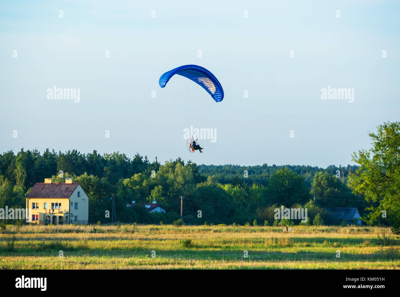 Paraglider flies over with his parachute in the countryside in Poland ...