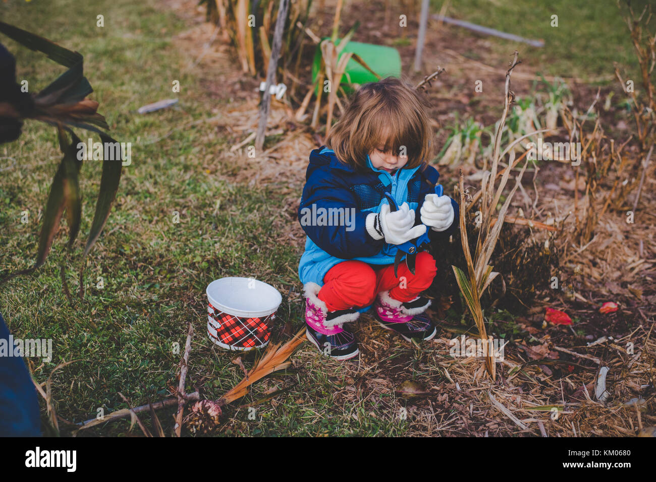Children helping their grandfather dig in a garden during the winter ...