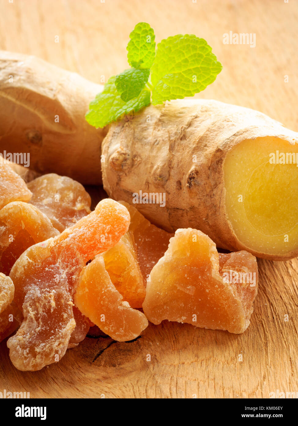 Closeup dried candied crystallized ginger pieces and raw root on wooden ...