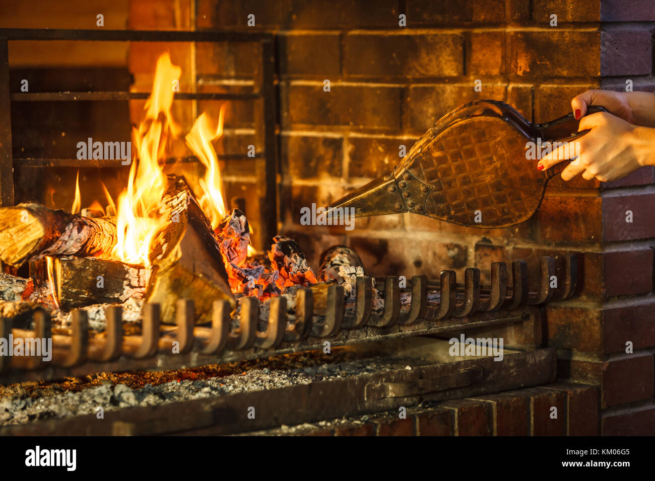 Closeup of human hands at fireplace making fire with bellows. Person ...