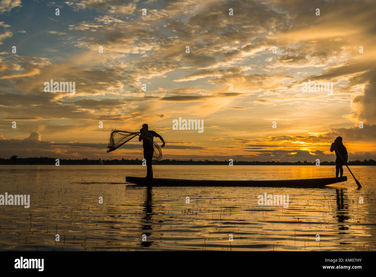 Fisherman is fishing by using fishing net on the river during evening ...