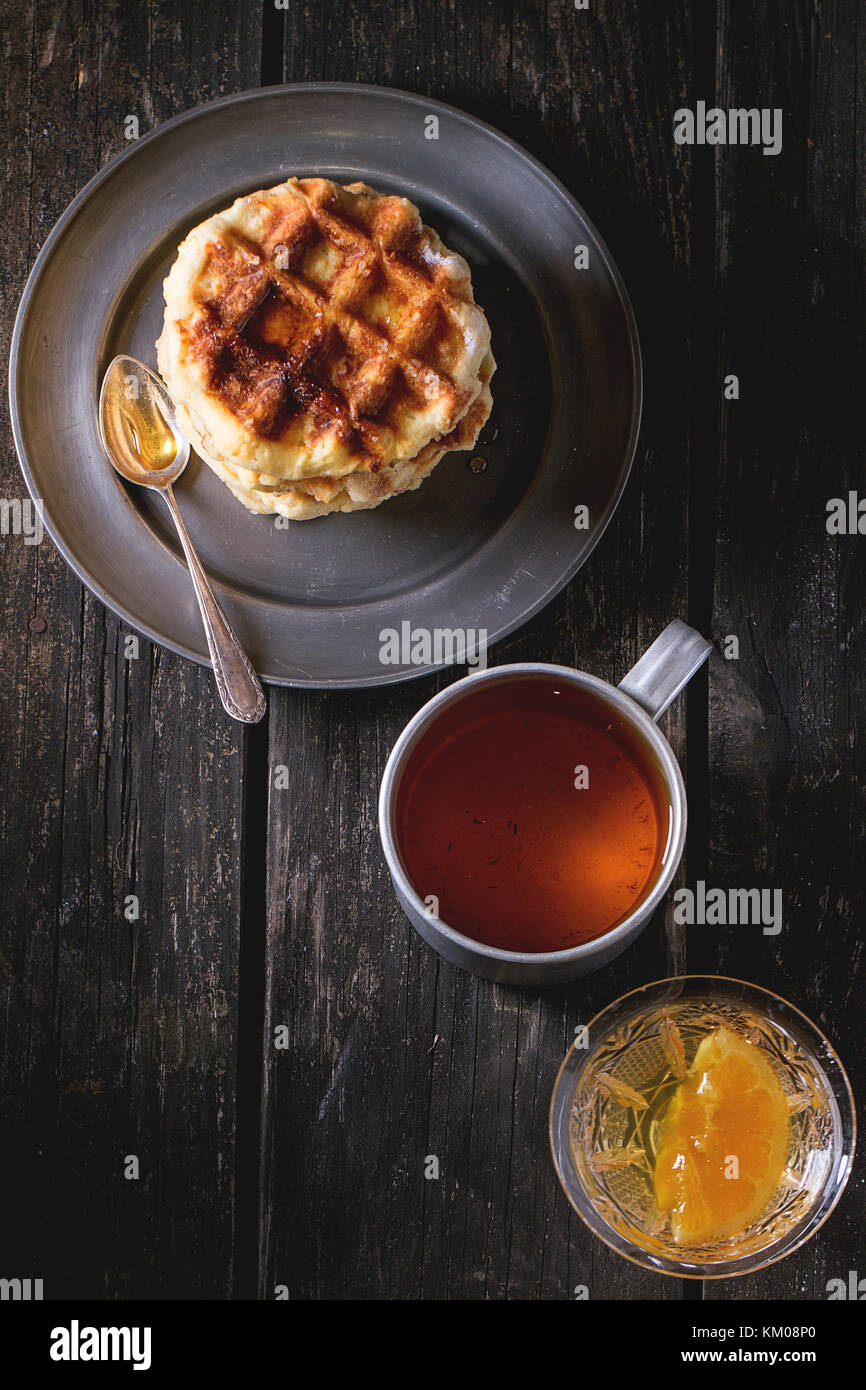 Metal plate with homemade belgian waffles with orange syrup in vase and ...