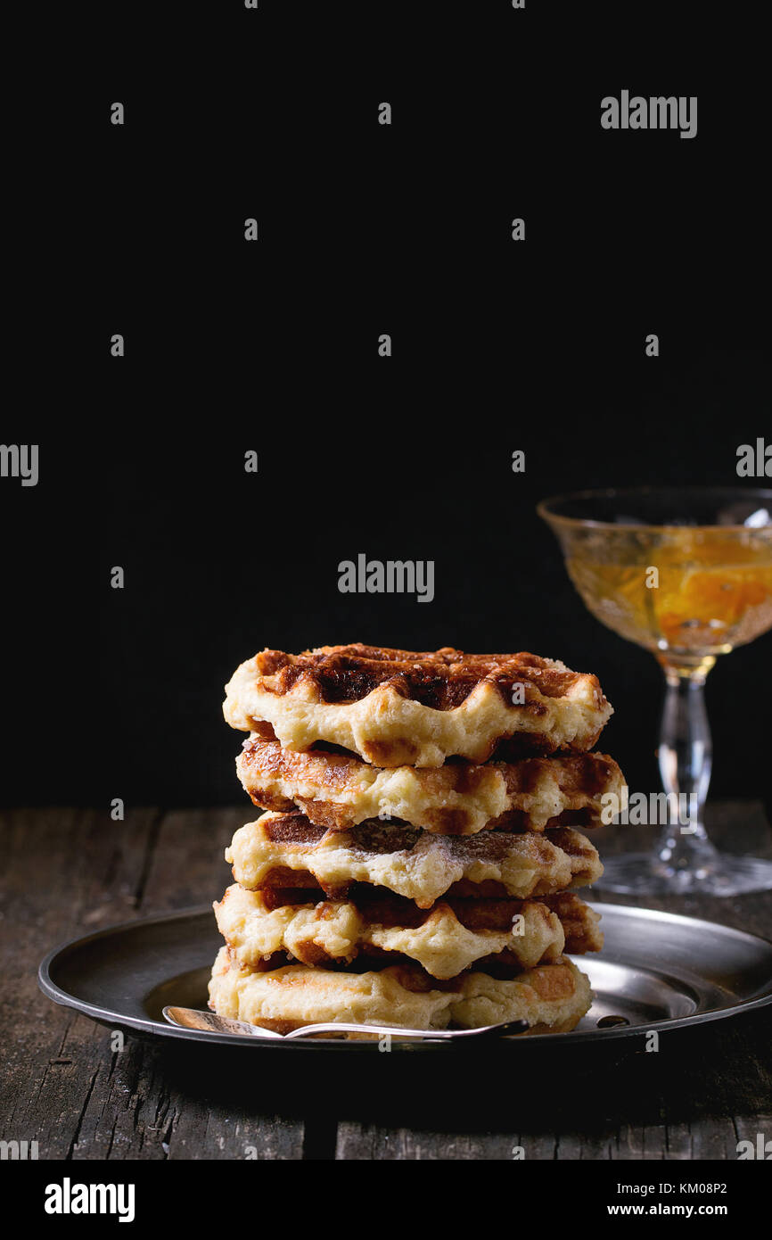 Metal plate with homemade belgian waffles with orange syrup in vase at ...