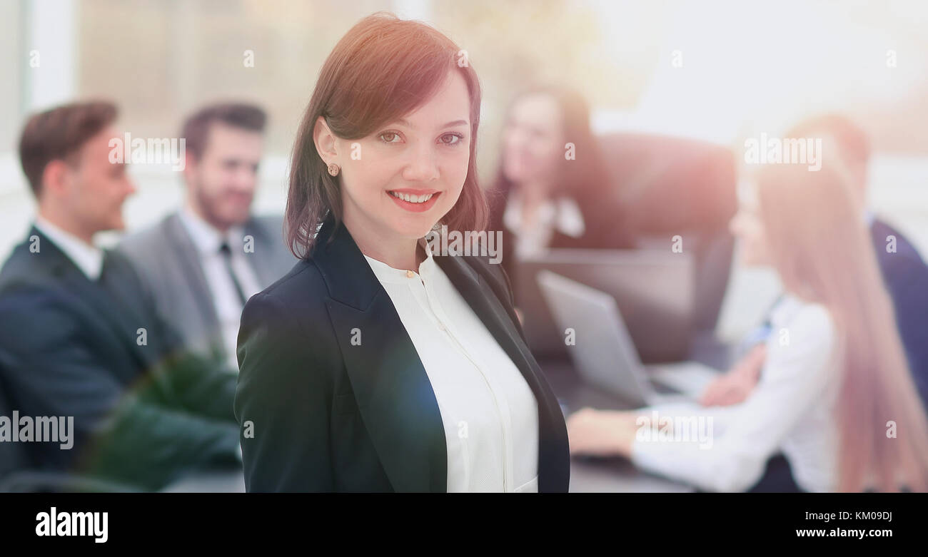 Successful business woman standing with her staff in background at ...