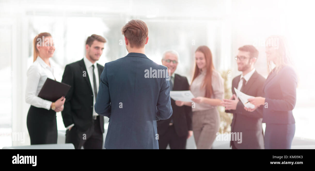 Successful business man standing with his staff in background at Stock ...