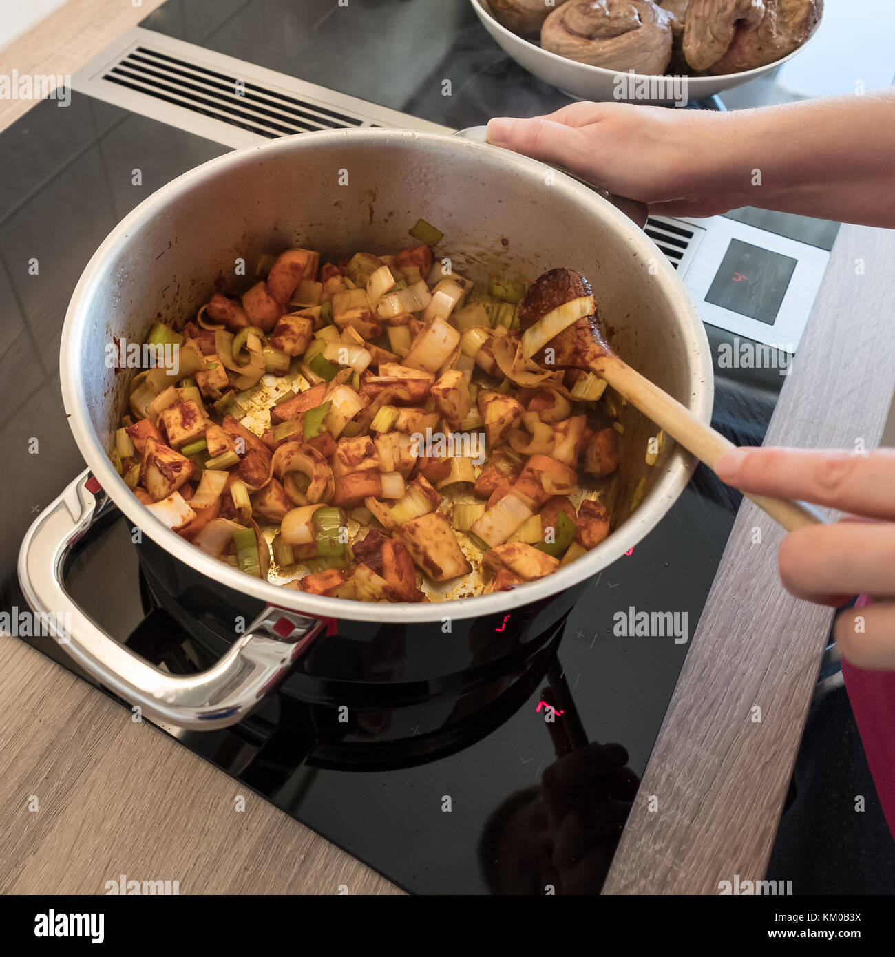 Female hand braising vegetables with wooden spoon in a saucepan Stock ...