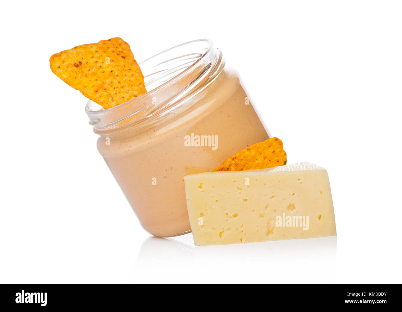 Glass container with cheese dip and nachos chips on white background ...