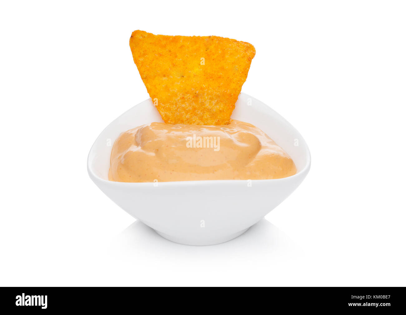 Glass container with cheese dip and nachos chips on white background ...