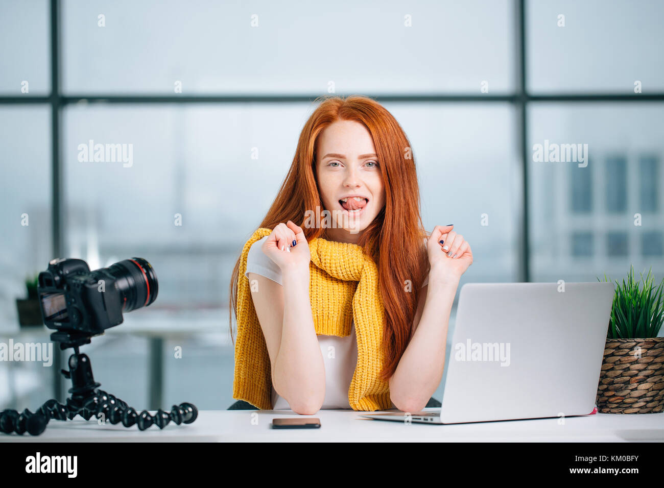 Young woman working on computer with cameras and accessories on table ...