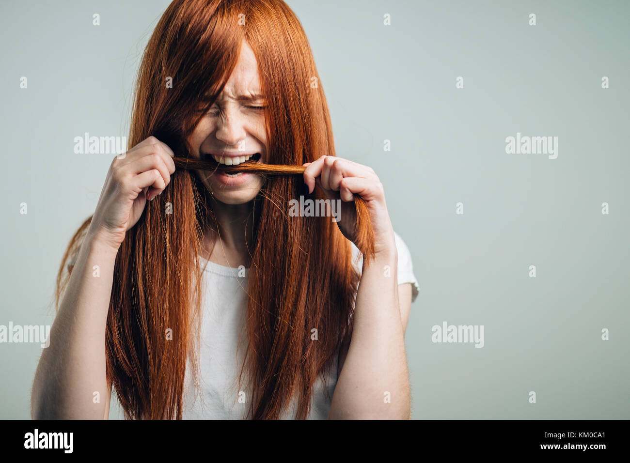 Sad redhead girl bite her damaged hair Stock Photo - Alamy