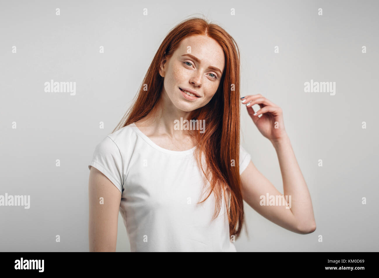 girl smiling with closed eyes touching her red hair over white background Stock Photo - Alamy