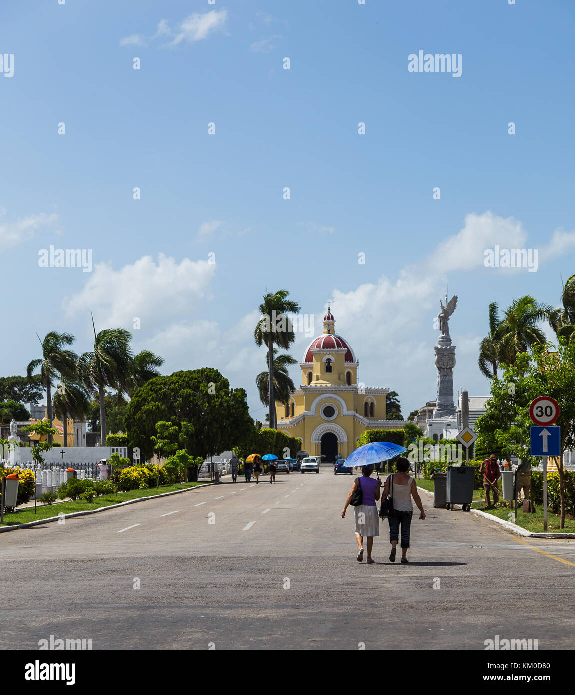 Two middle aged women walk towards the main chapel in Colon Cemetery to ...