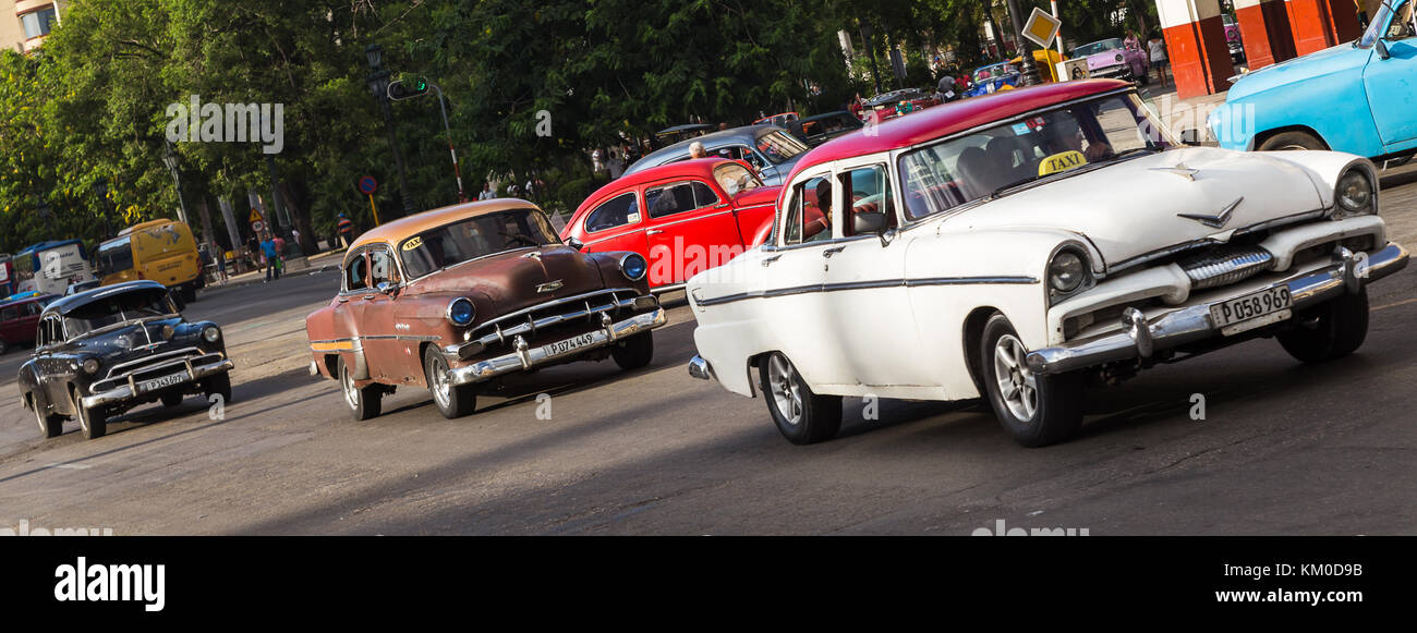 A trio of different coloured classical cars captured in a slanted ...