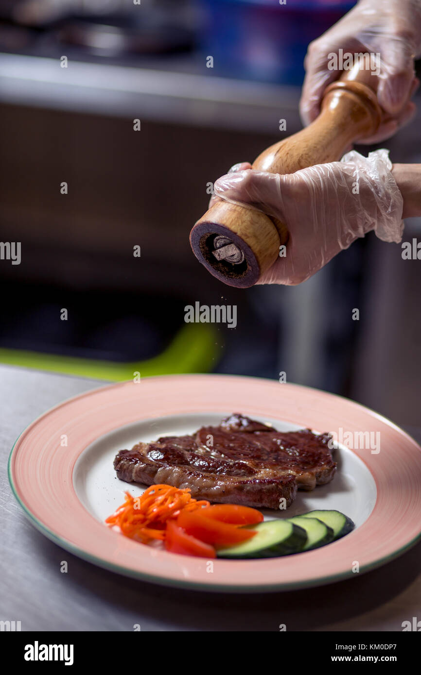 Chef in restaurant kitchen cooking, hands to be seen, he is seasoning ...