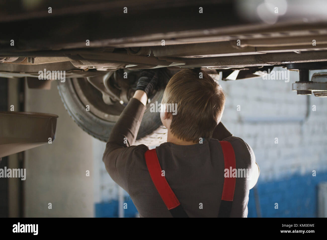 Mechanic unscrewing parts of automobile's bottom under lifted car Stock ...