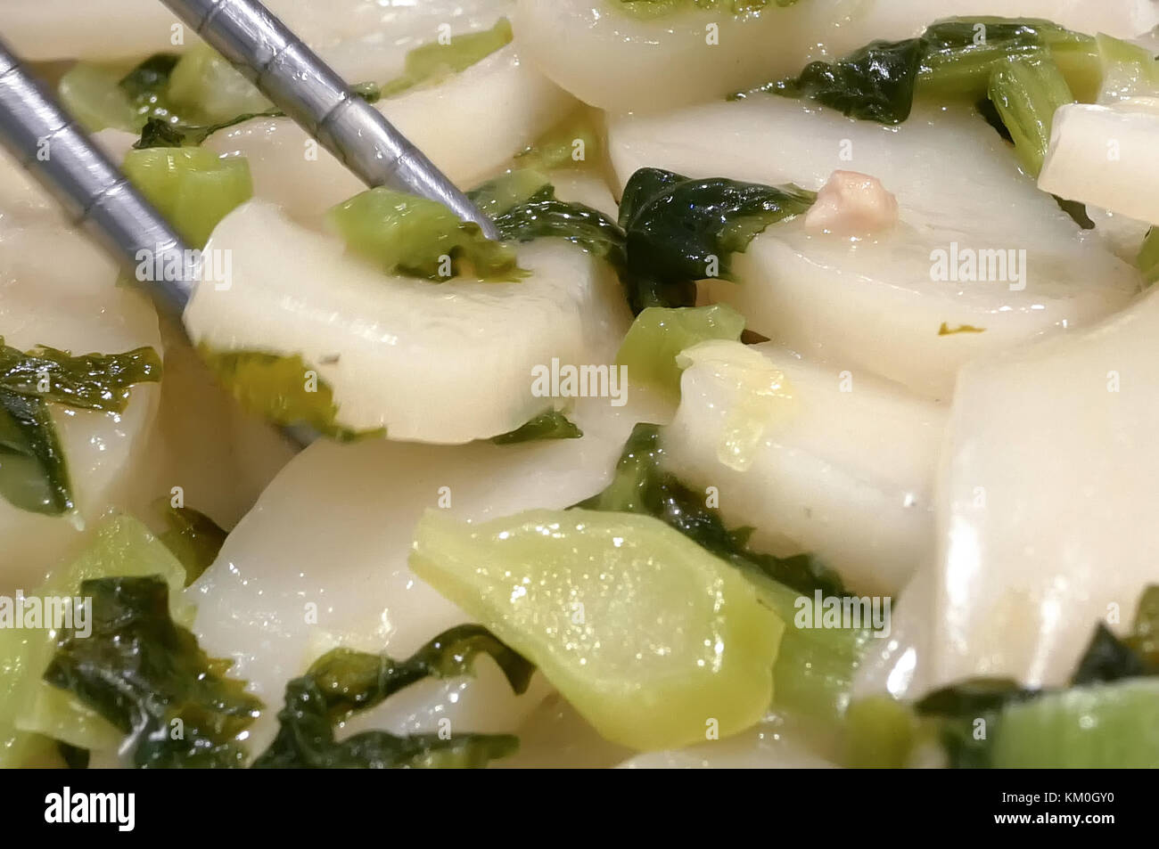Close up of people eating fried rice cake with vegetable on table ...
