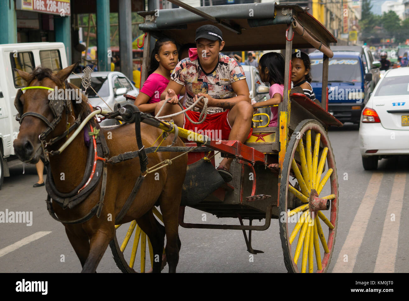 A horse drawn carriage known as a Kalesa being driven in downtown Cebu ...