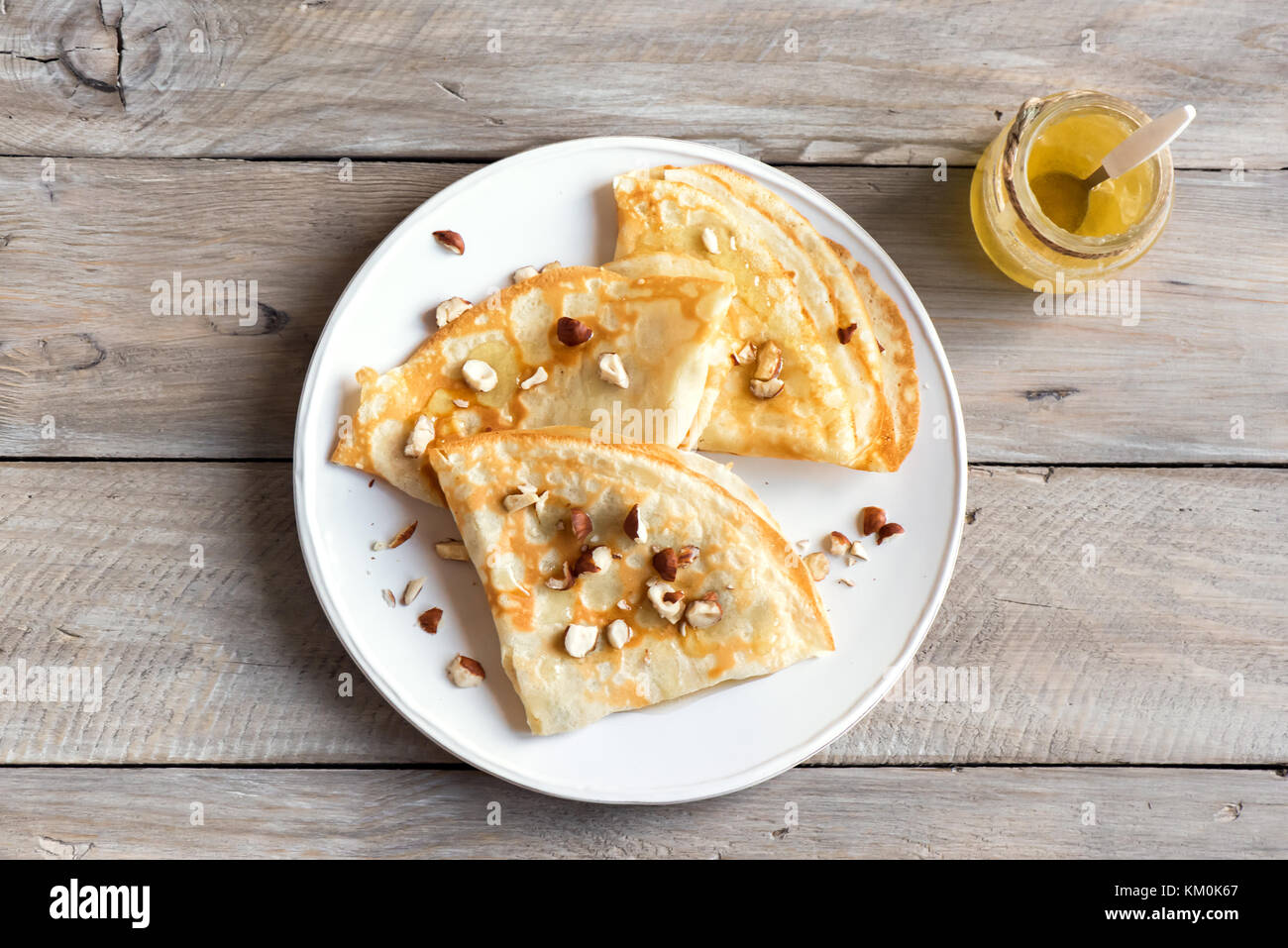 Crepes Suzette with honey and nuts on white plate over wooden ...