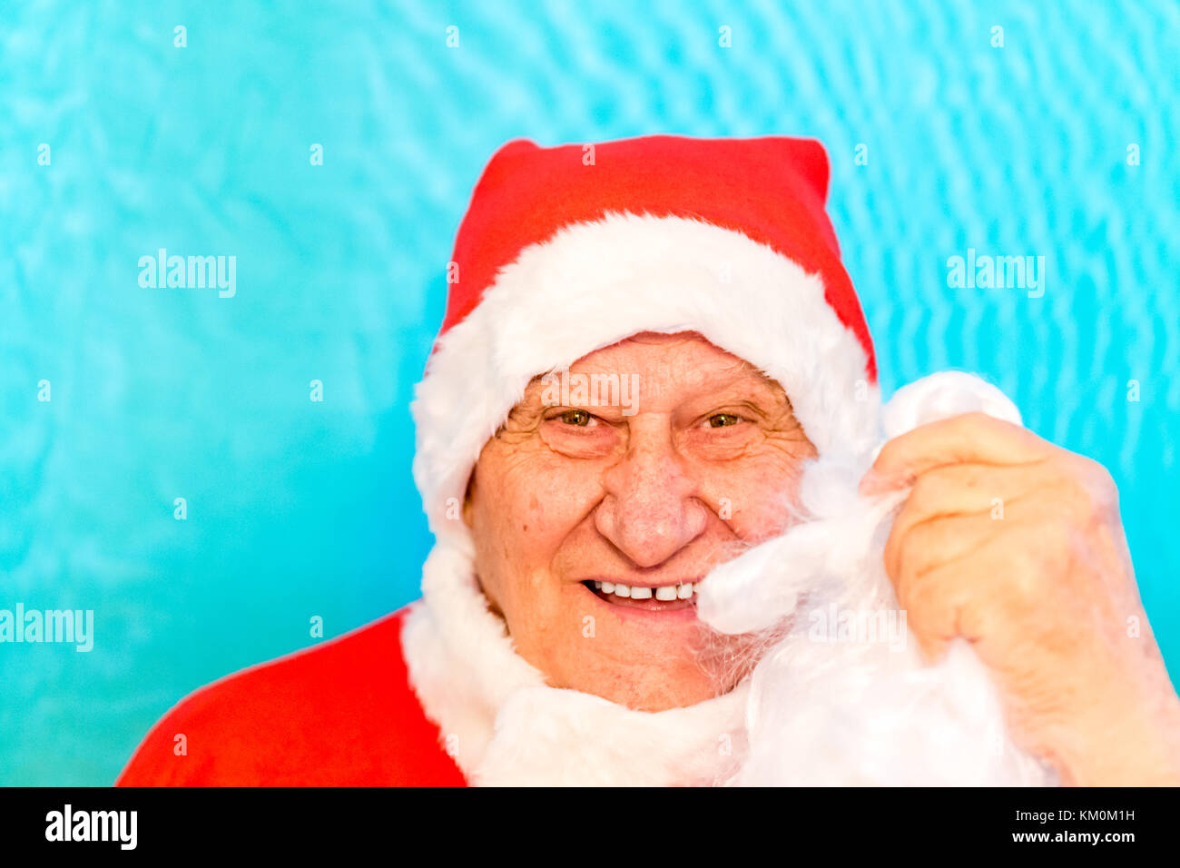 old man wearing Santa Claus costume smiling and taking off fake beard ...