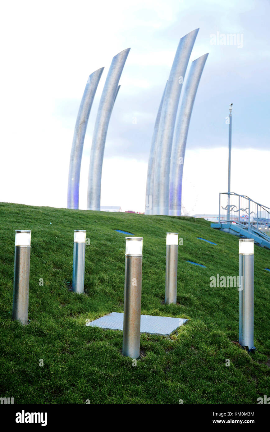 Group of illuminated bollards on grass in front of curved steel vents ...