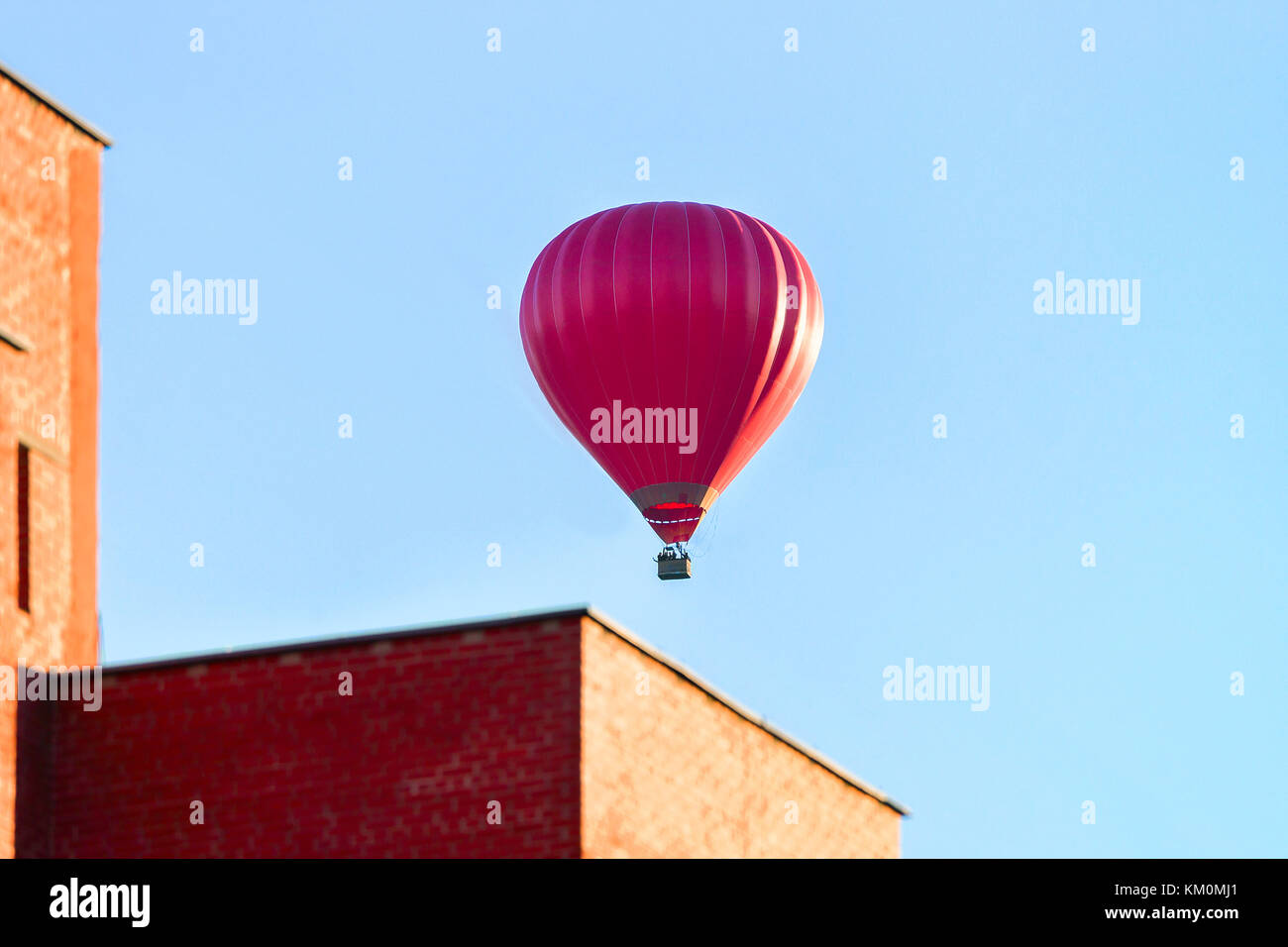 Red air balloon flying over the residential house building in the city ...