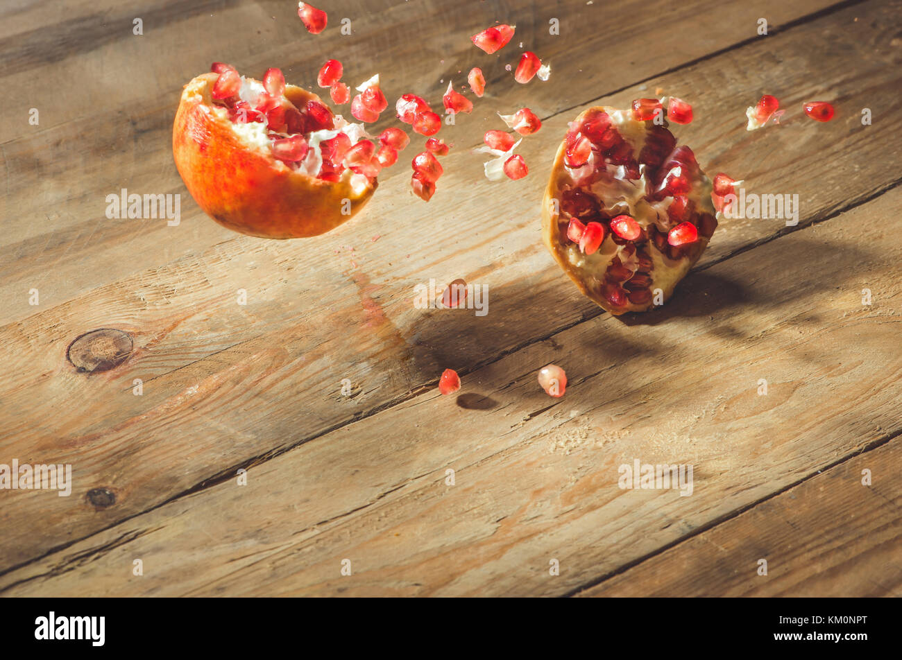 Falling down ripe pomegranate with cracks and splashes of juice and ...