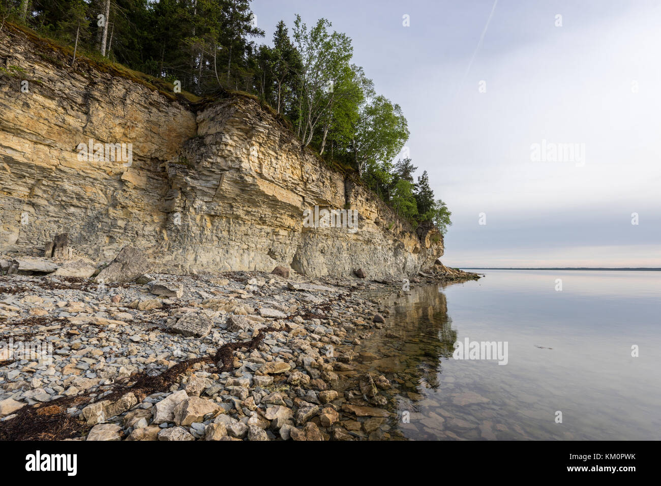 Sunset on the beach. Limestone cliff in the sea under blue sky and ...