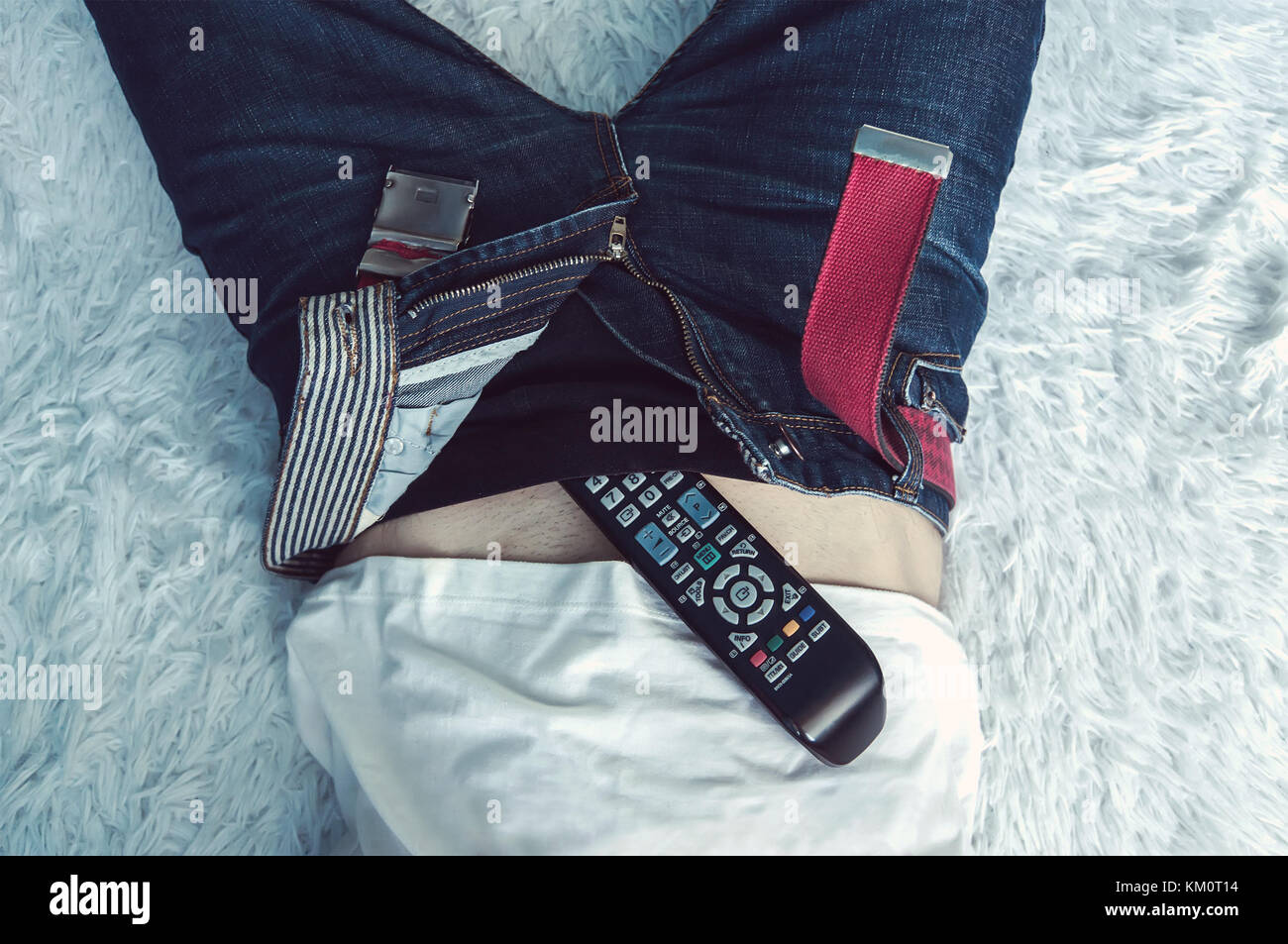 Man lying in bed and watching TV with the TV remote in his underpants ...