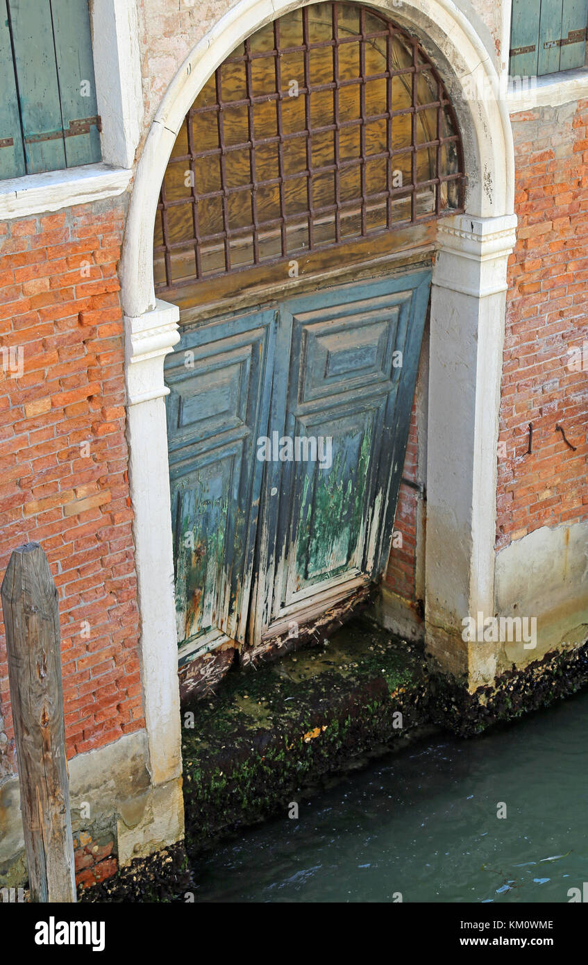 rotten broken wooden gate on a canal of the island of Venice in Italy ...