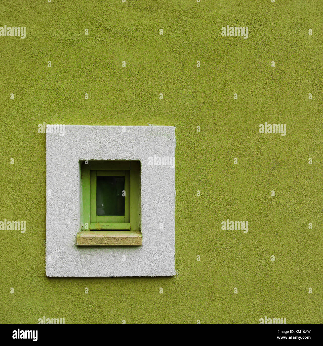 Small square green window on a green plastered wall with a white frame ...