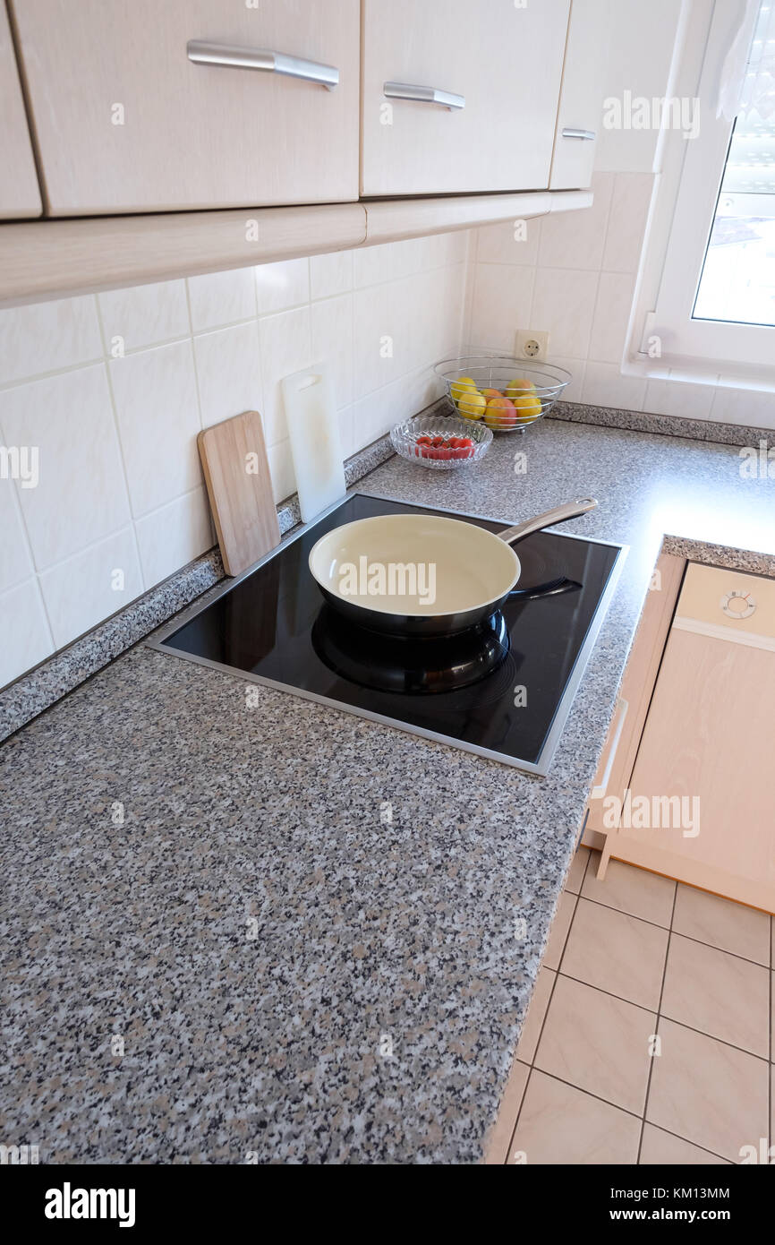 Fitted kitchen with ceramic hob and frying pan in vertical format Stock ...