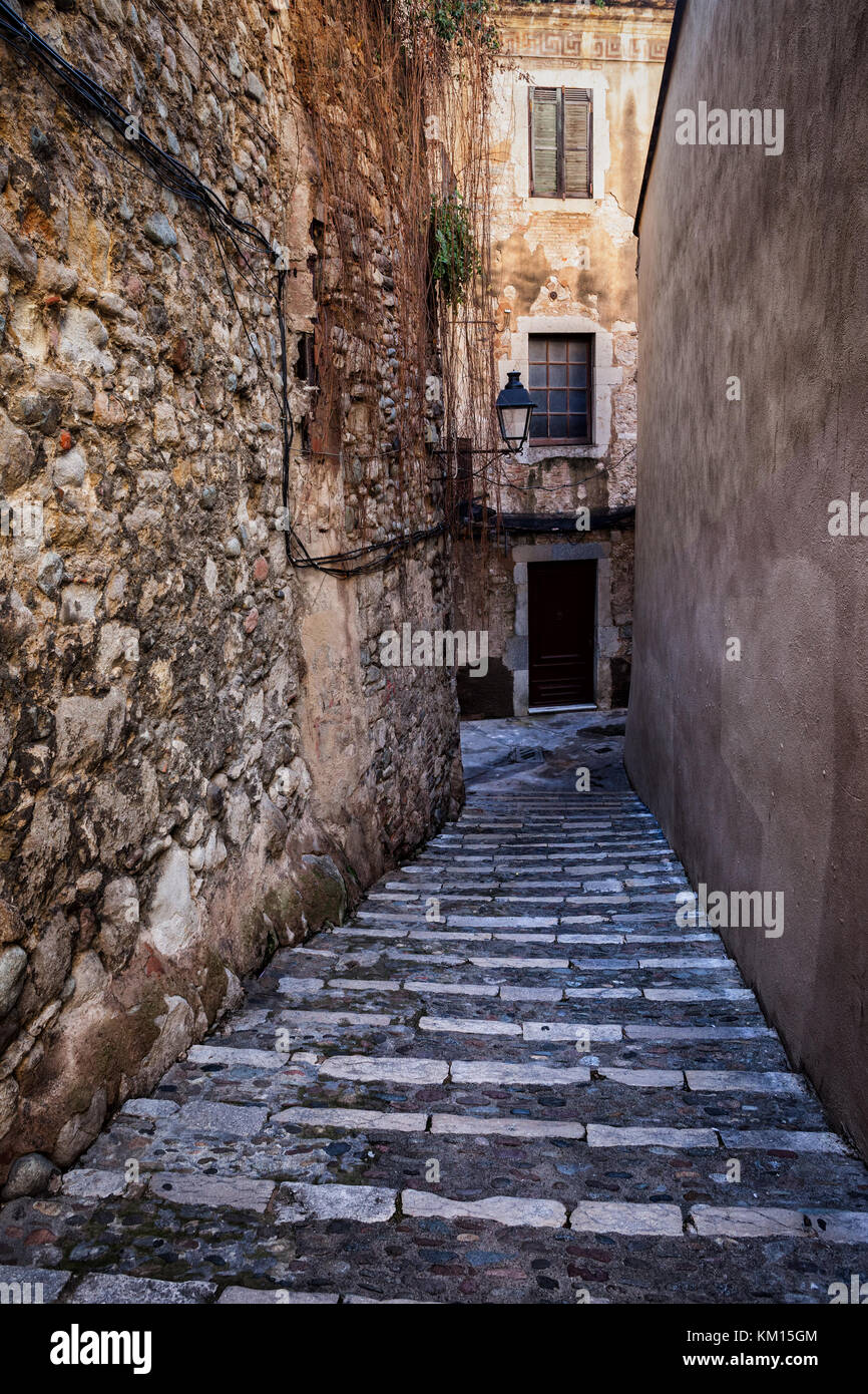 Narrow cobbled alley with stairs along medieval stone wall in Old ...