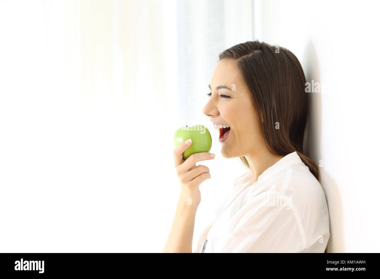 Side view portrait of a happy woman eating an apple isolated on white ...