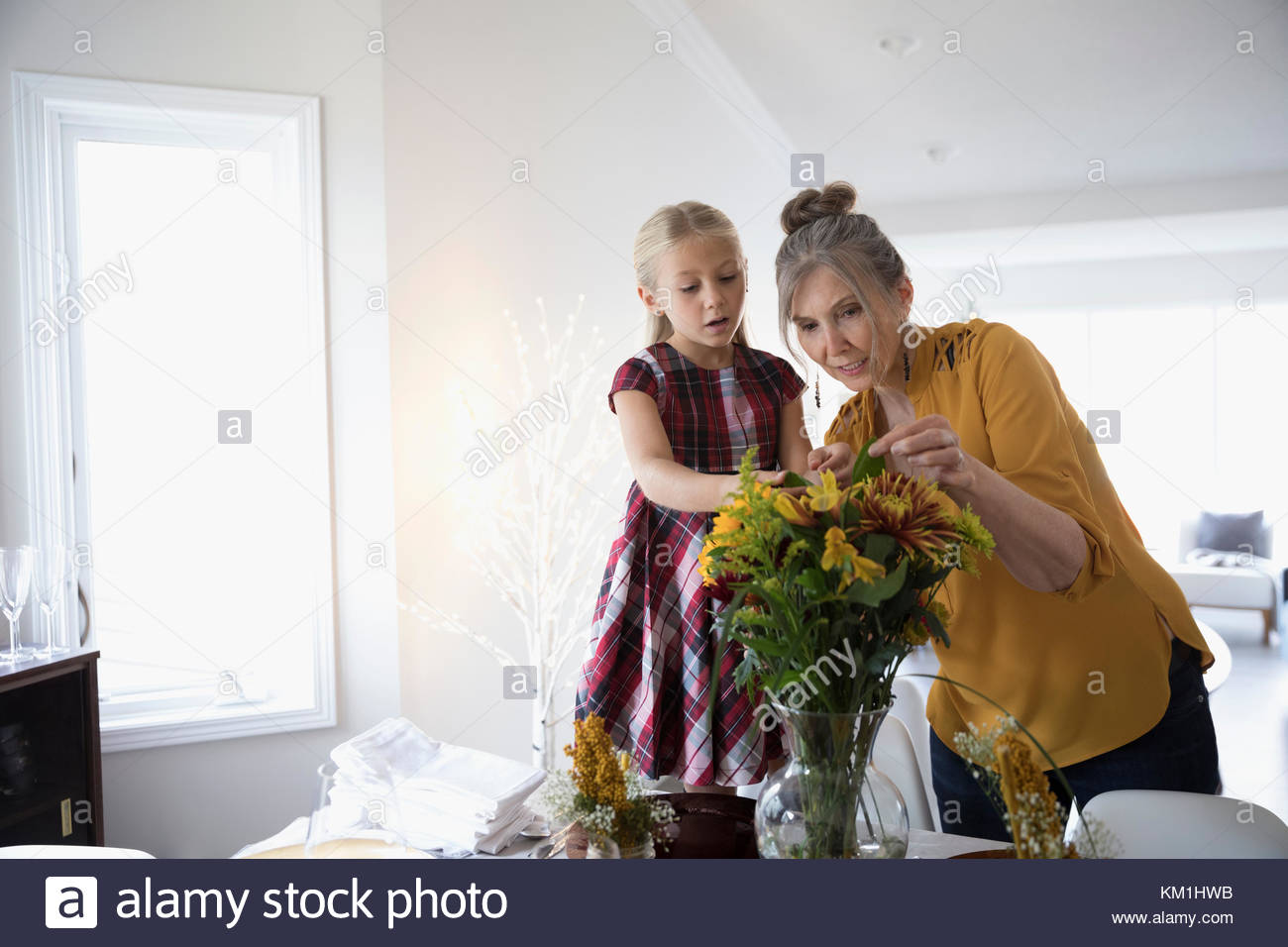 Grandmother And Granddaughter Arranging Flower Bouquet On Dinner Table