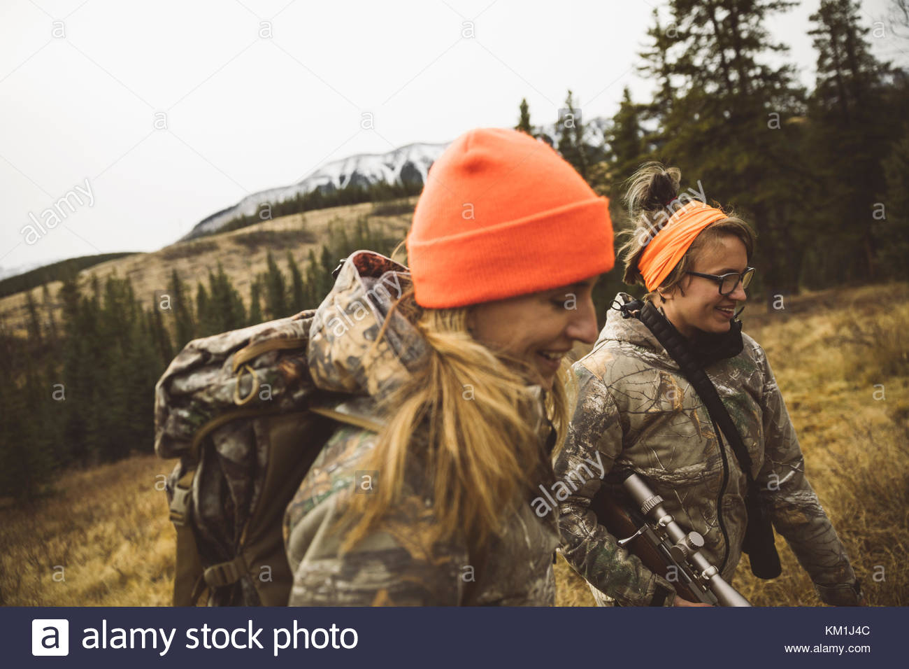Smiling mother and daughter hunters with hunting rifle walking in ...