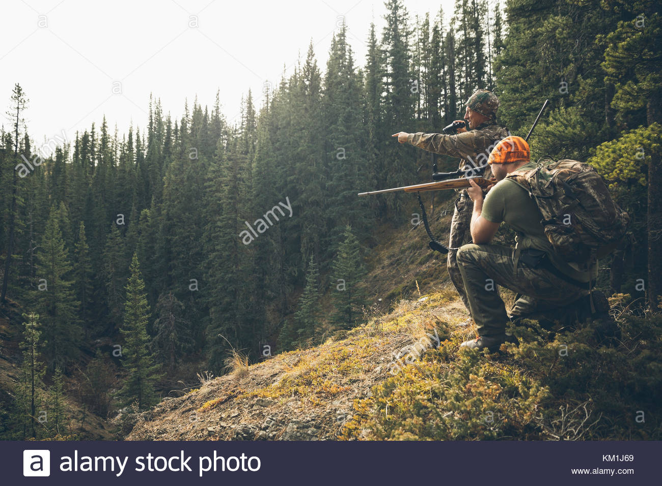 Father and son hunters aiming and shooting hunting rifles on forest ...