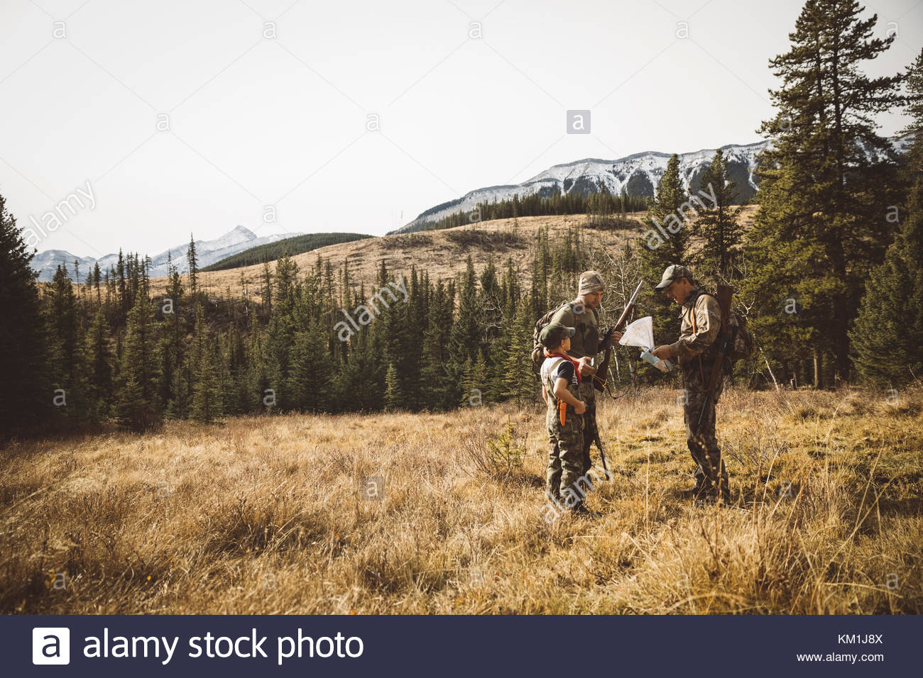 Multi-generation male hunters with map and hunting rifles in remote ...