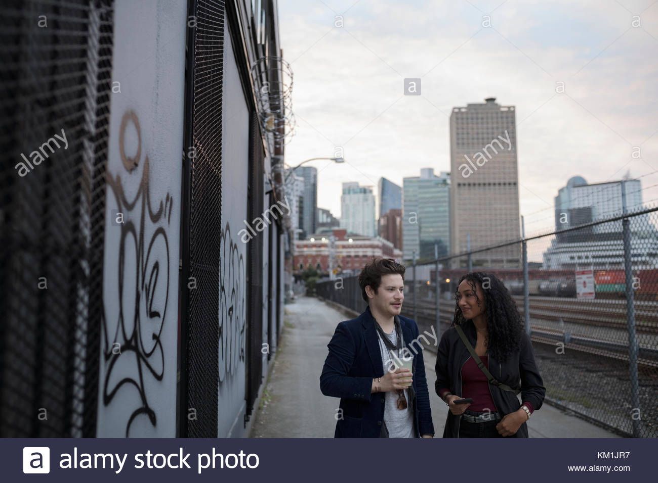 Young couple walking along urban railroad tracks Stock Photo - Alamy