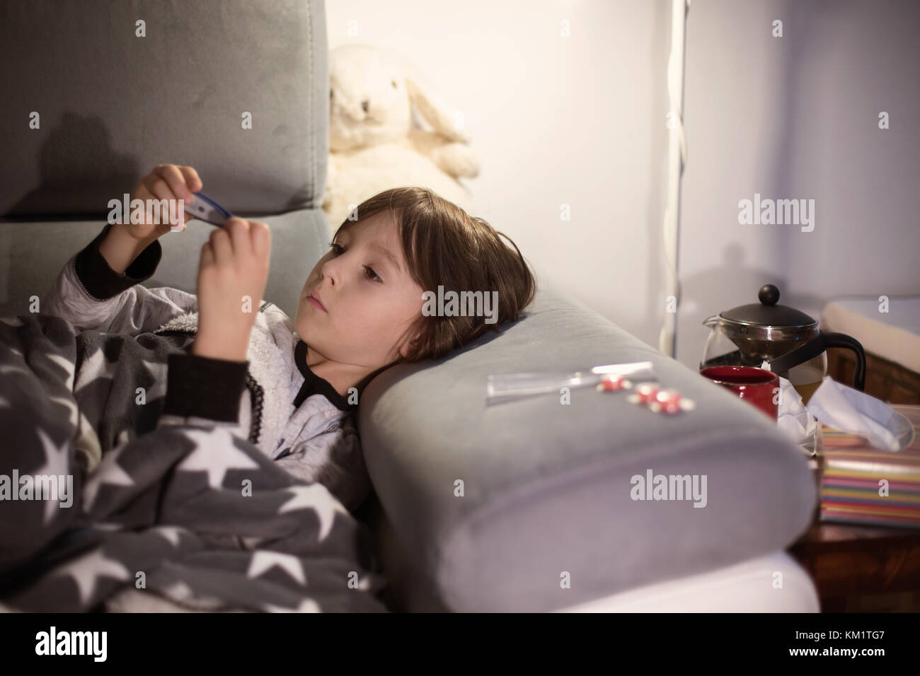 Sick child boy lying on the sofa with a fever, resting at home Stock ...