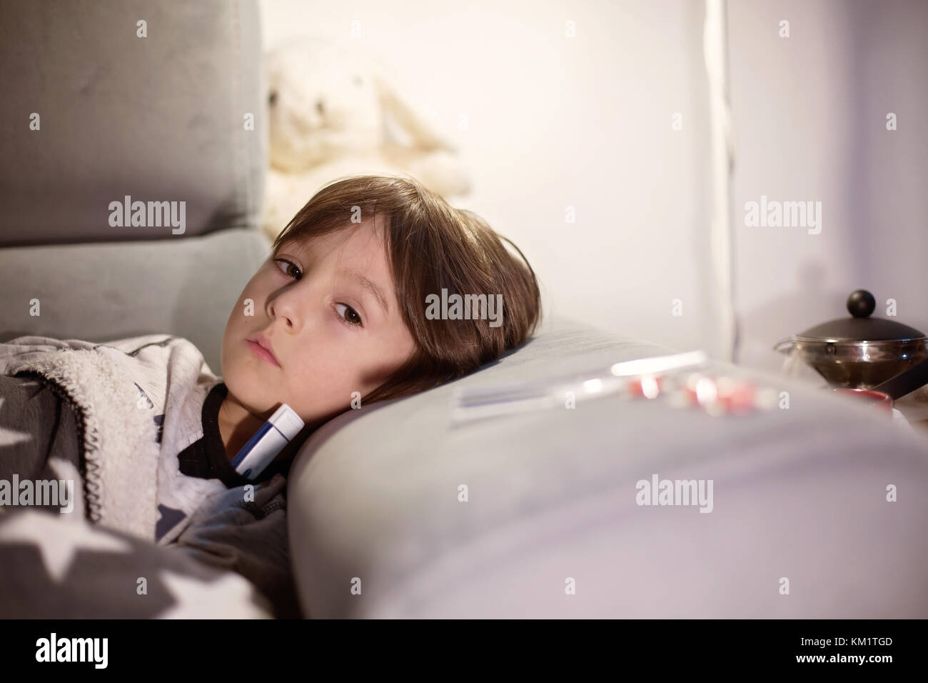 Sick child boy lying on the sofa with a fever, resting at home Stock ...